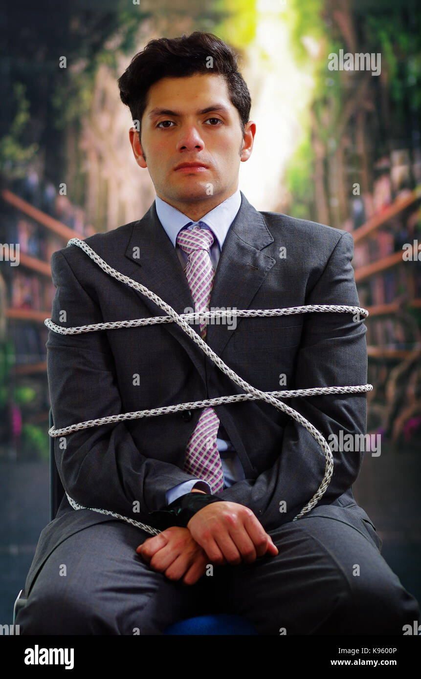 Businessman trapped in a chair with rope in a blurred background Stock ...