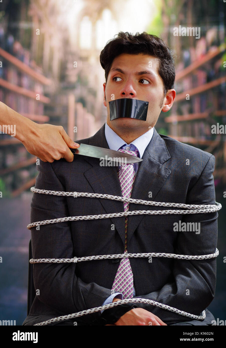 Businessman trapped in a chair with rope, with a black tape in his ...