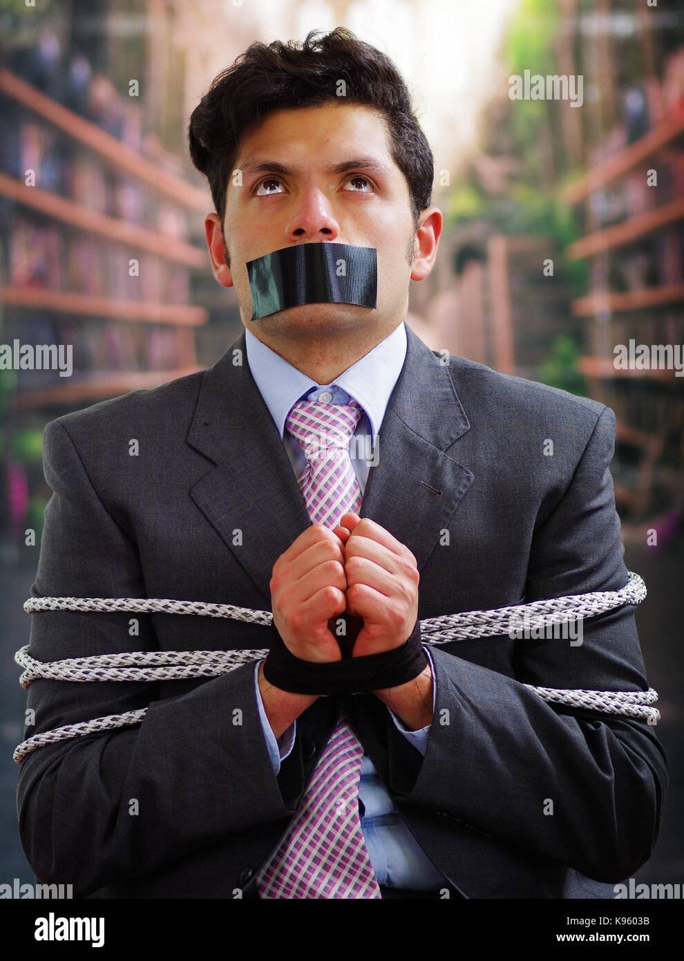 Businessman trapped in a chair with rope, with a black tape in his ...