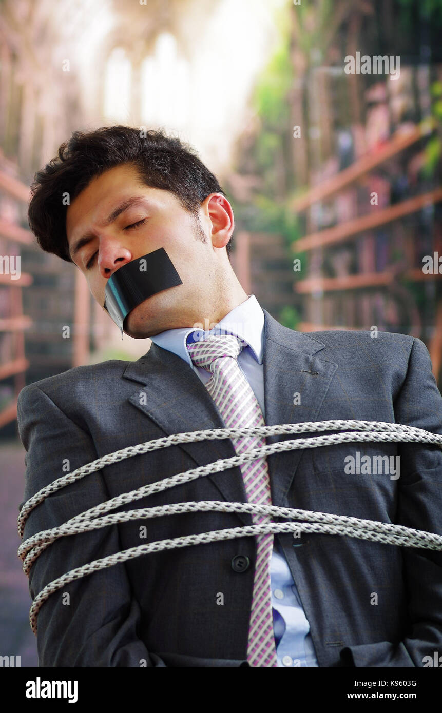 Businessman trapped in a chair with rope, with a black tape in his ...