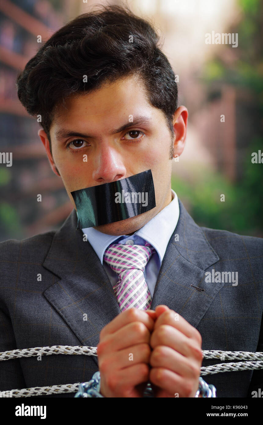 Close up of a businessman trapped in a chair with rope, with a black ...