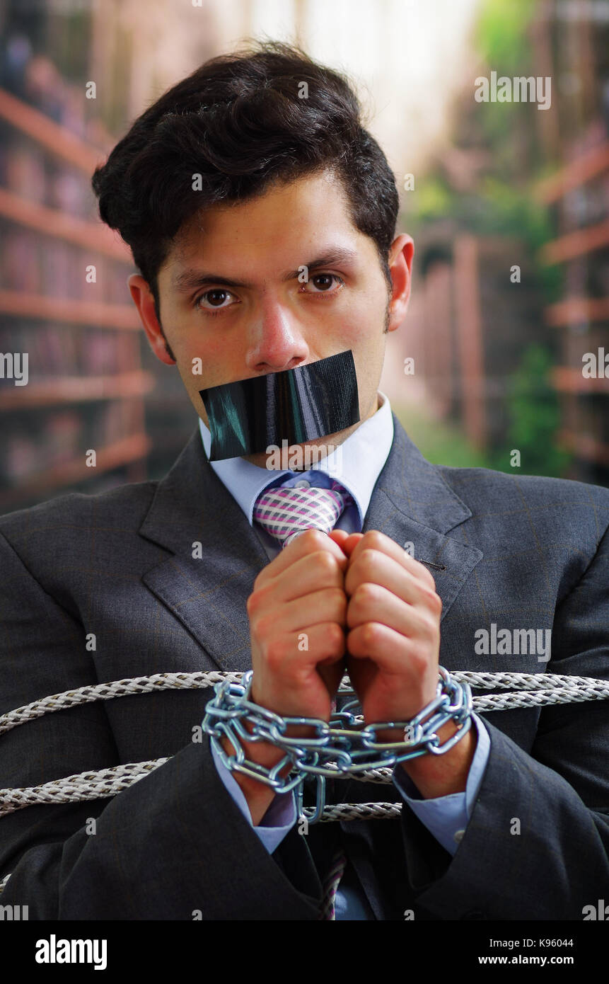 Close up of a businessman trapped in a chair with rope, with a black ...