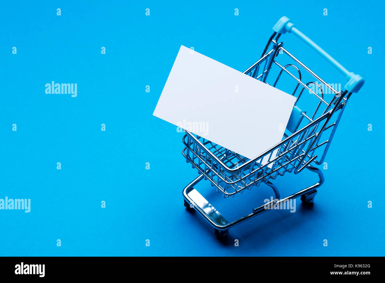 Shopping cart on a blue background with blank label Stock Photo - Alamy