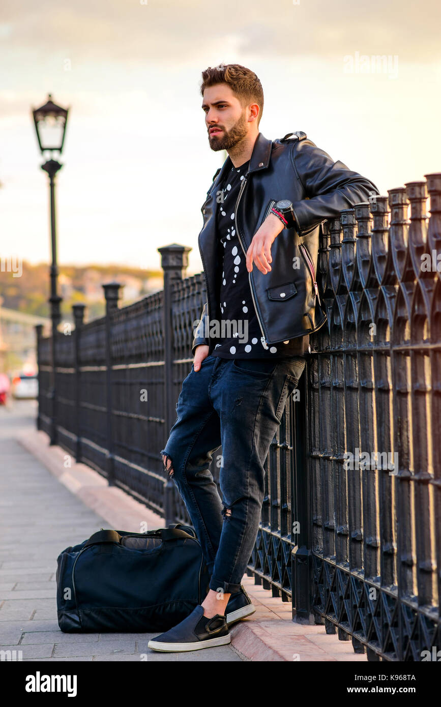 A Handsome Young Hipster Man Leaning To The Fences And Looking Around