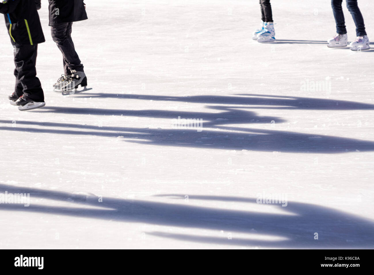 Back view of skaters and their shadows on ice rink in wintertime Stock ...
