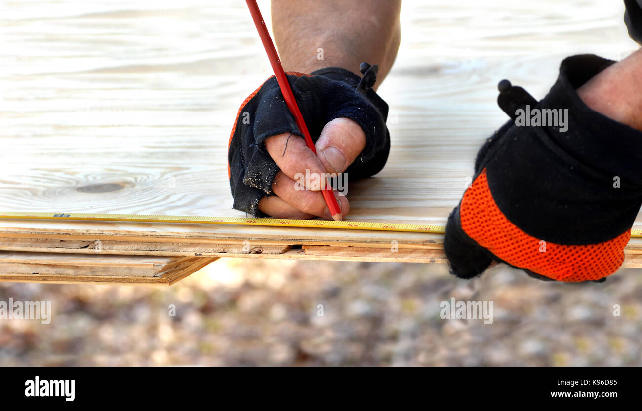 Carpenter makes marks using his tape measure to know the exact place to ...