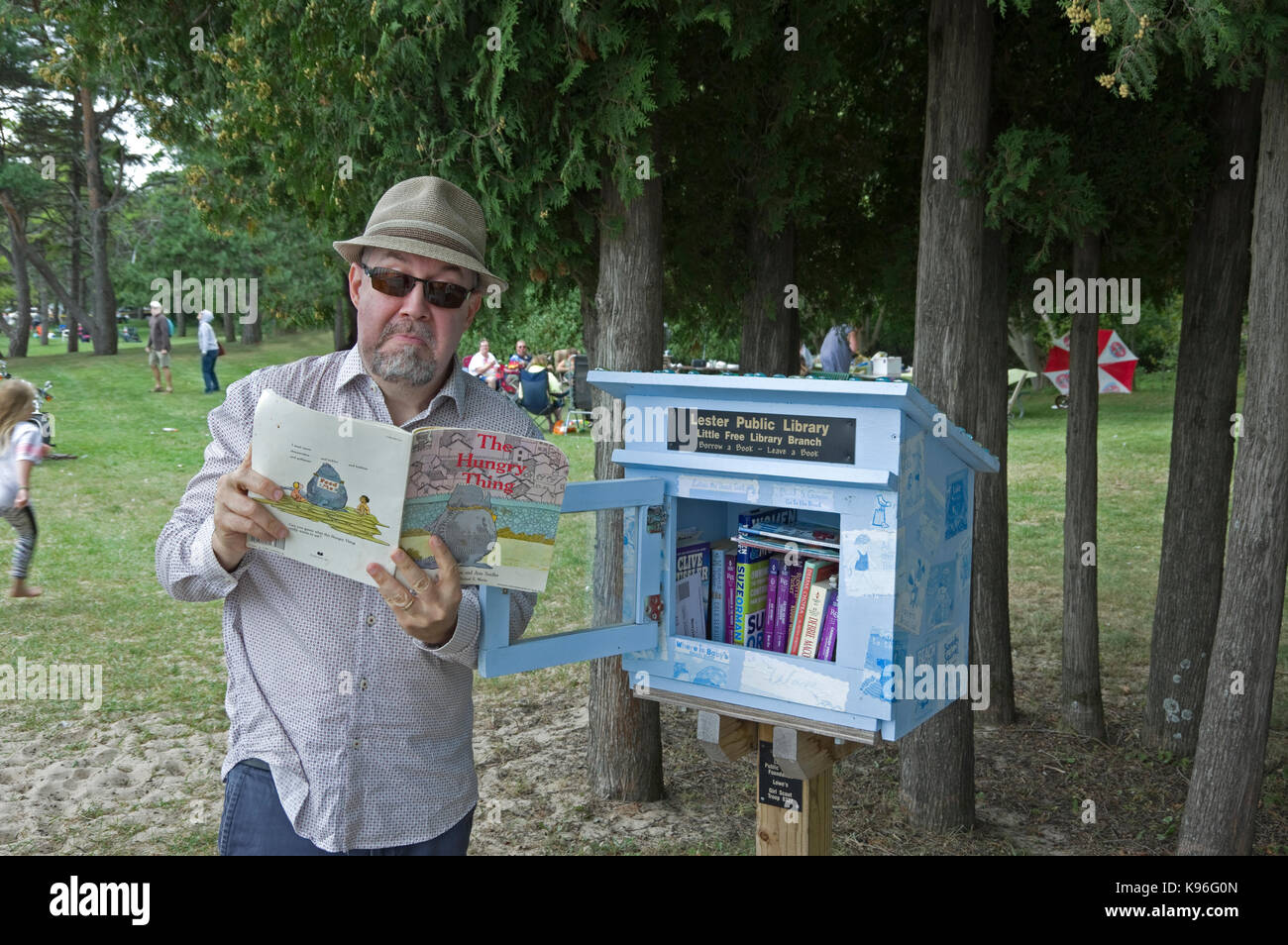 Man perusing book at Little Free Library book exchange sponsored by ...
