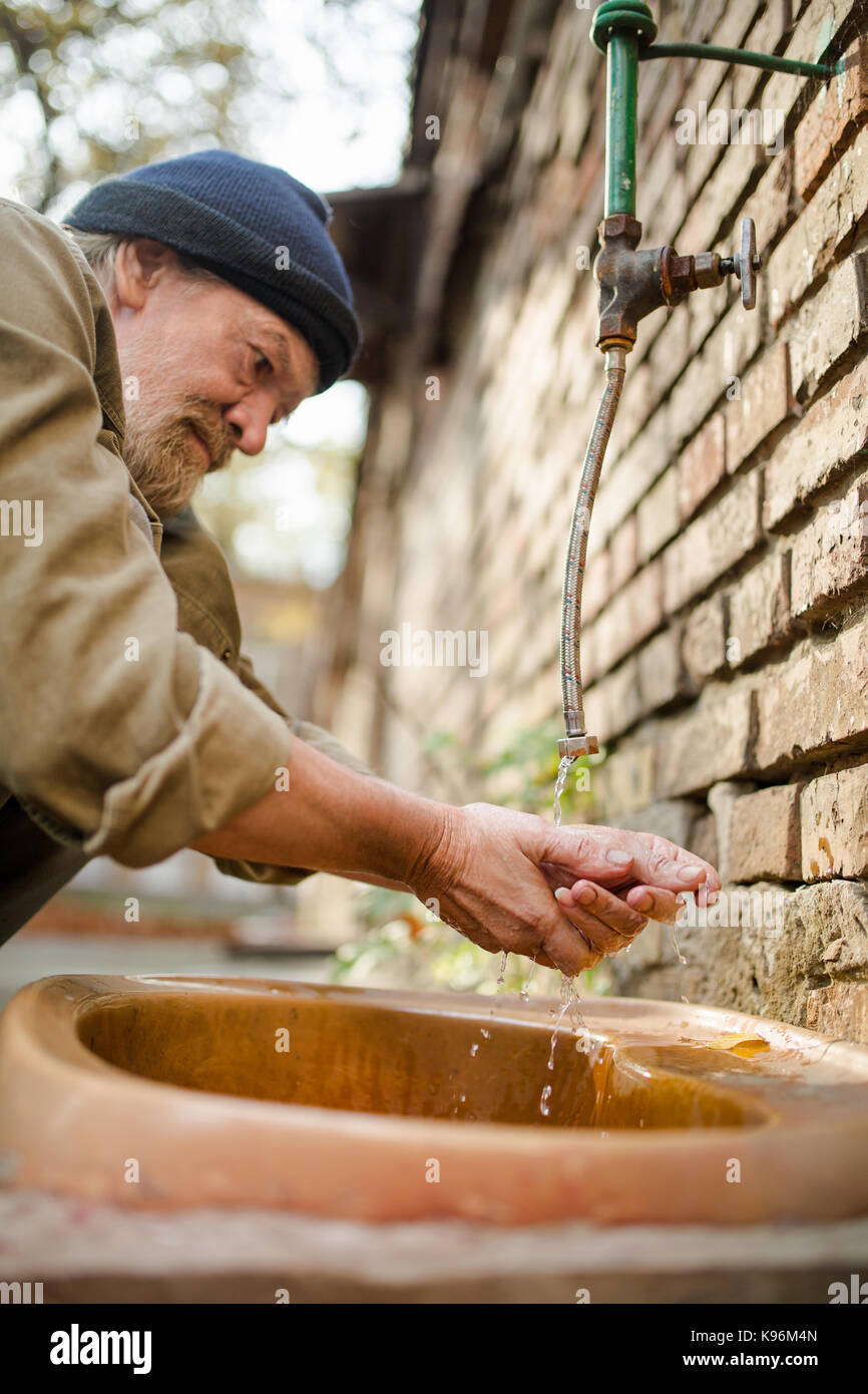 Homeless man washing hands in the street Stock Photo - Alamy