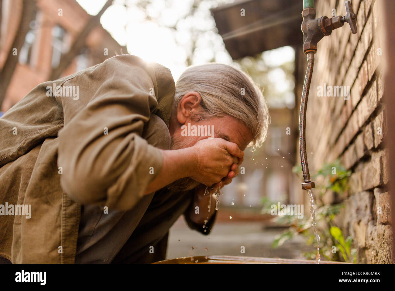 Close up view of homeless man washing face under running water Stock ...