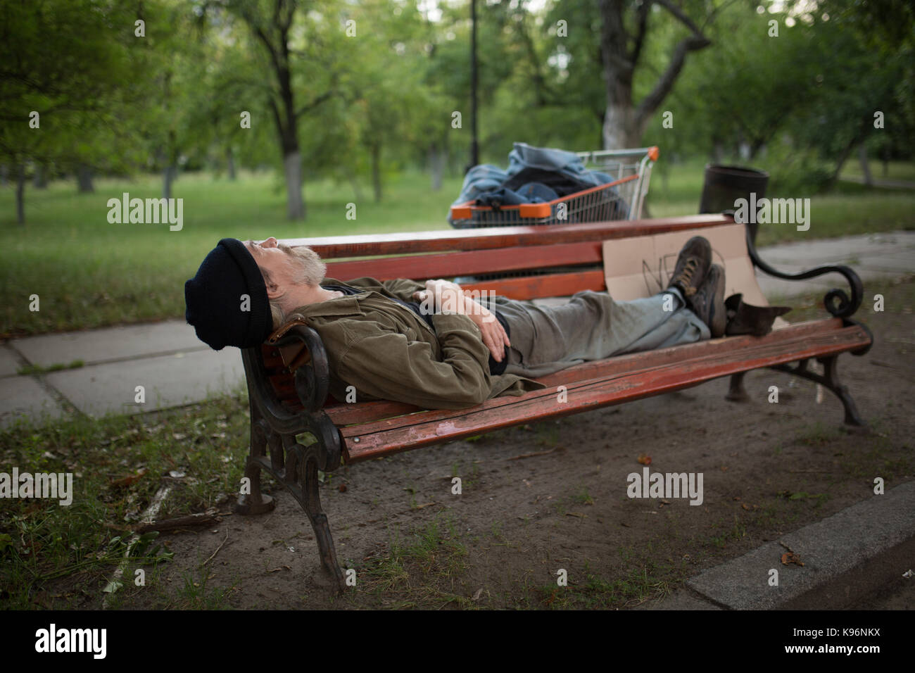 View of old man lying on bench in city park Stock Photo - Alamy