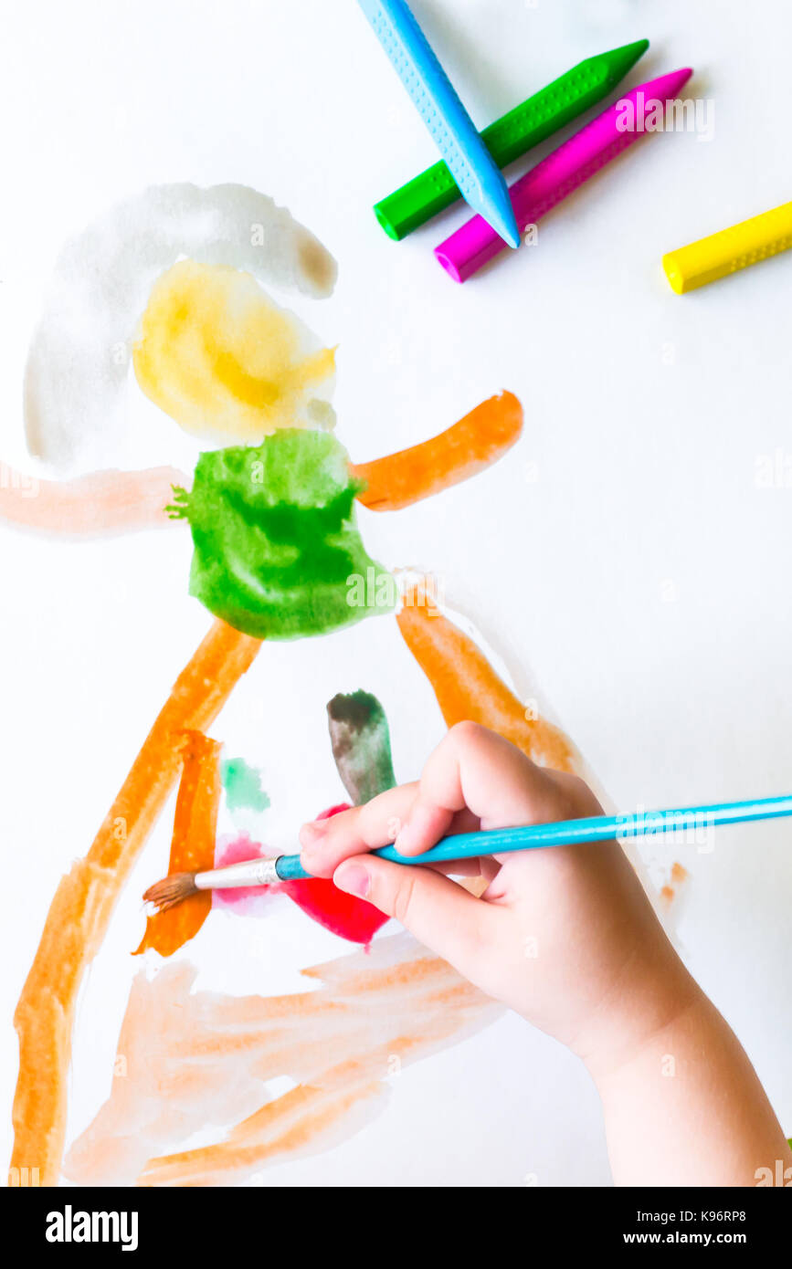 The child is drawing with a brush with acrylic paints on a blank sheet ...