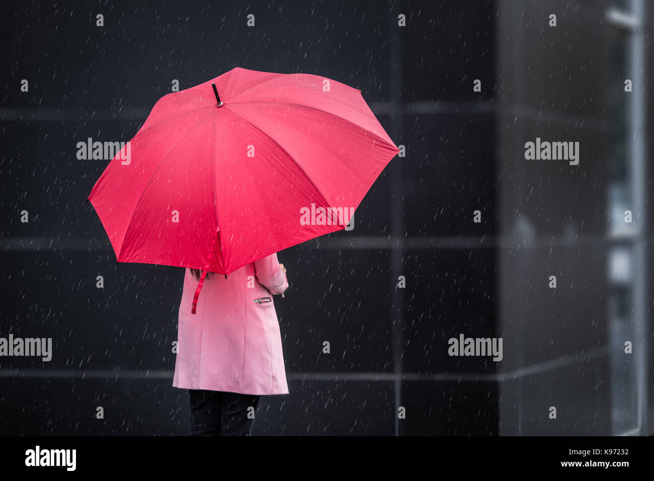Girl in Pink with red Umbrella on rainy day Stock Photo - Alamy