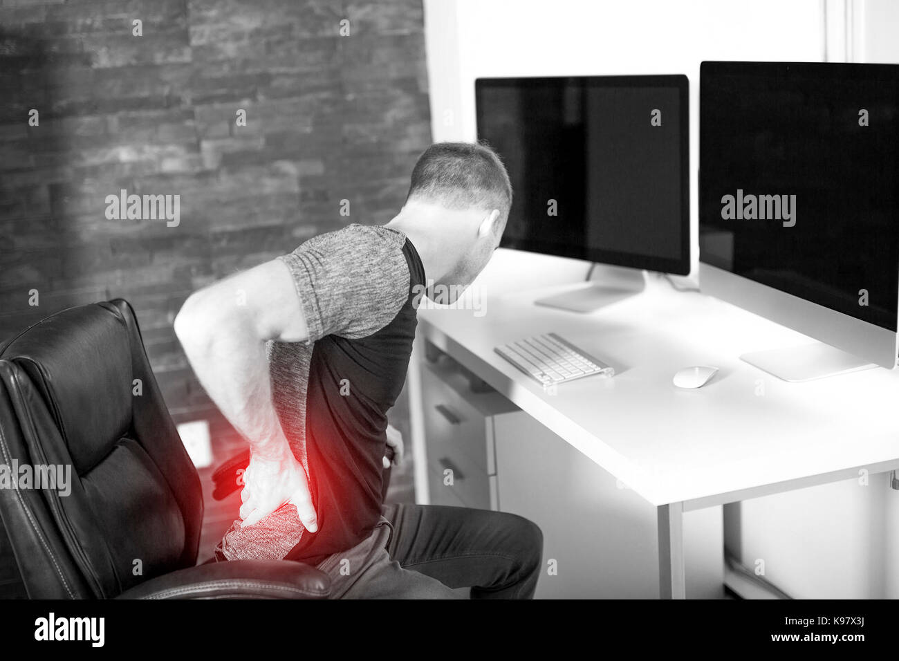 Man suffering from backache while sitting at computer desk in office ...