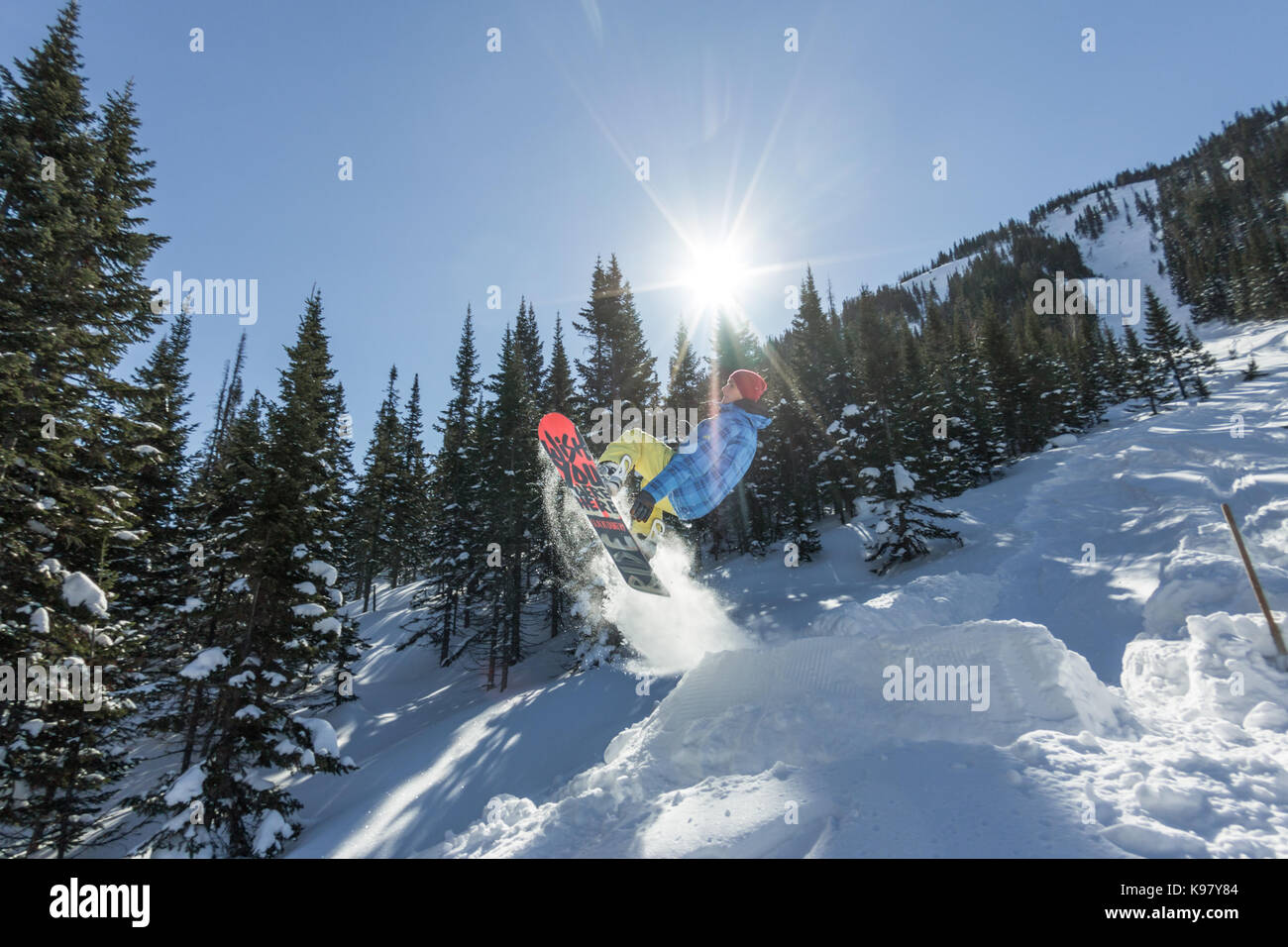 Snowboarder freerider jumping from a snow ramp in the sun on a ...