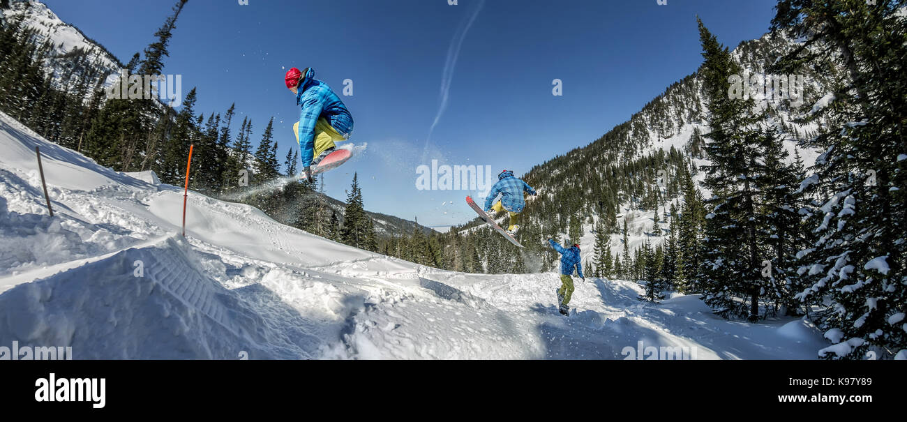 Panorama snowboarder freerider jumping from a snow ramp in the sun on a ...