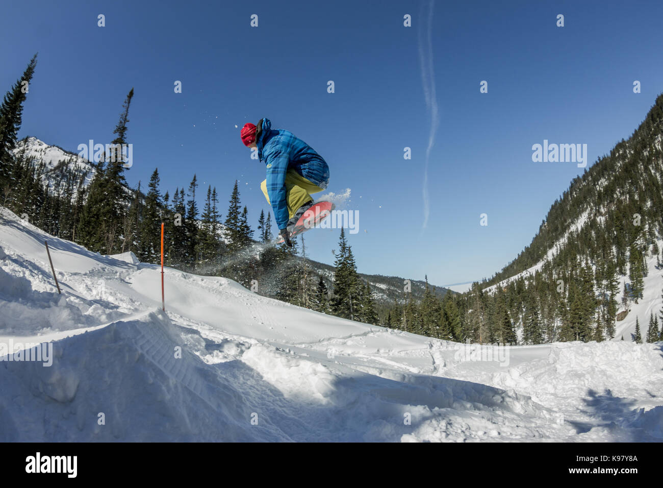 Snowboarder freerider jumping from a snow ramp in the sun on a ...