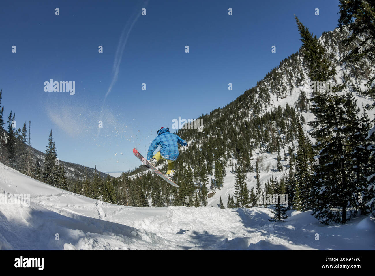 Snowboarder freerider jumping from a snow ramp in the sun on a ...
