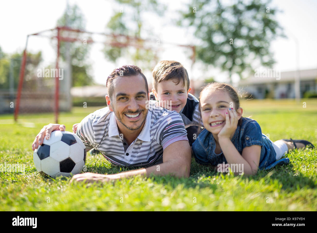 man with child playing football on field Stock Photo - Alamy