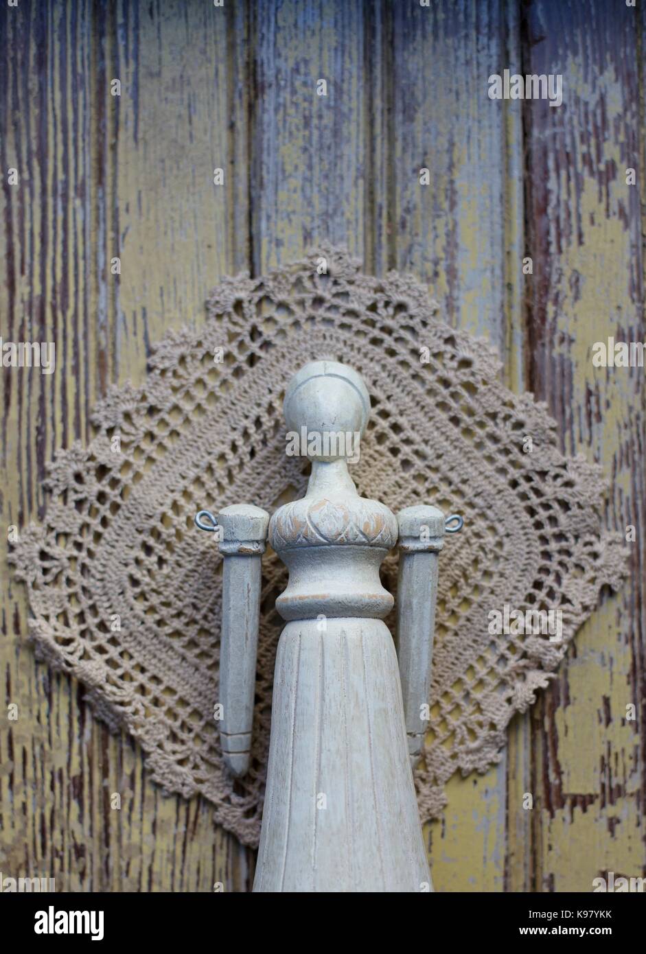 A carved wooden figurine of an old fashioned female figure, against a ...