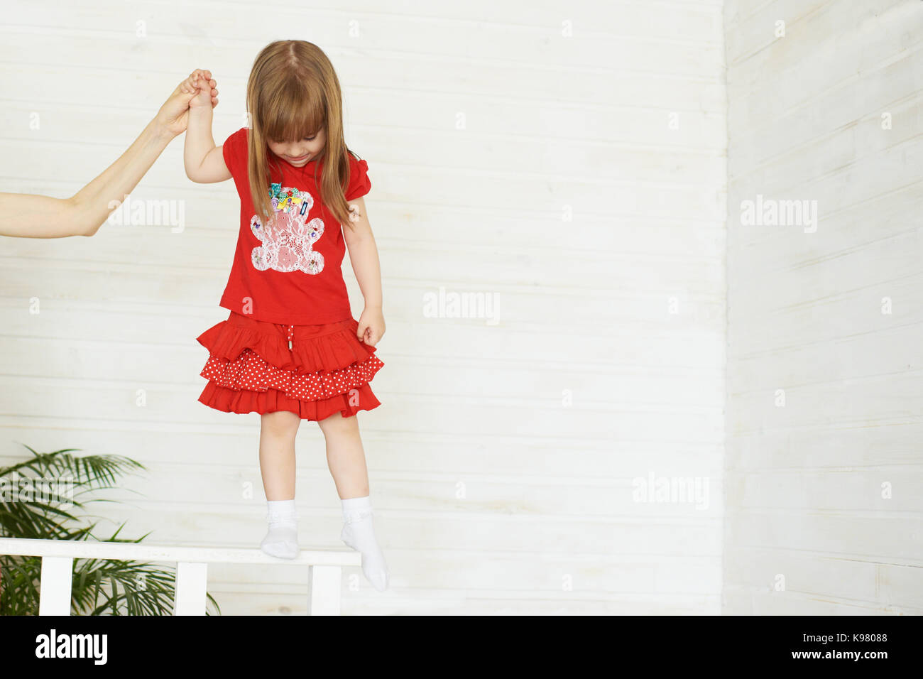 Young cute girl in red standing on railing Stock Photo - Alamy