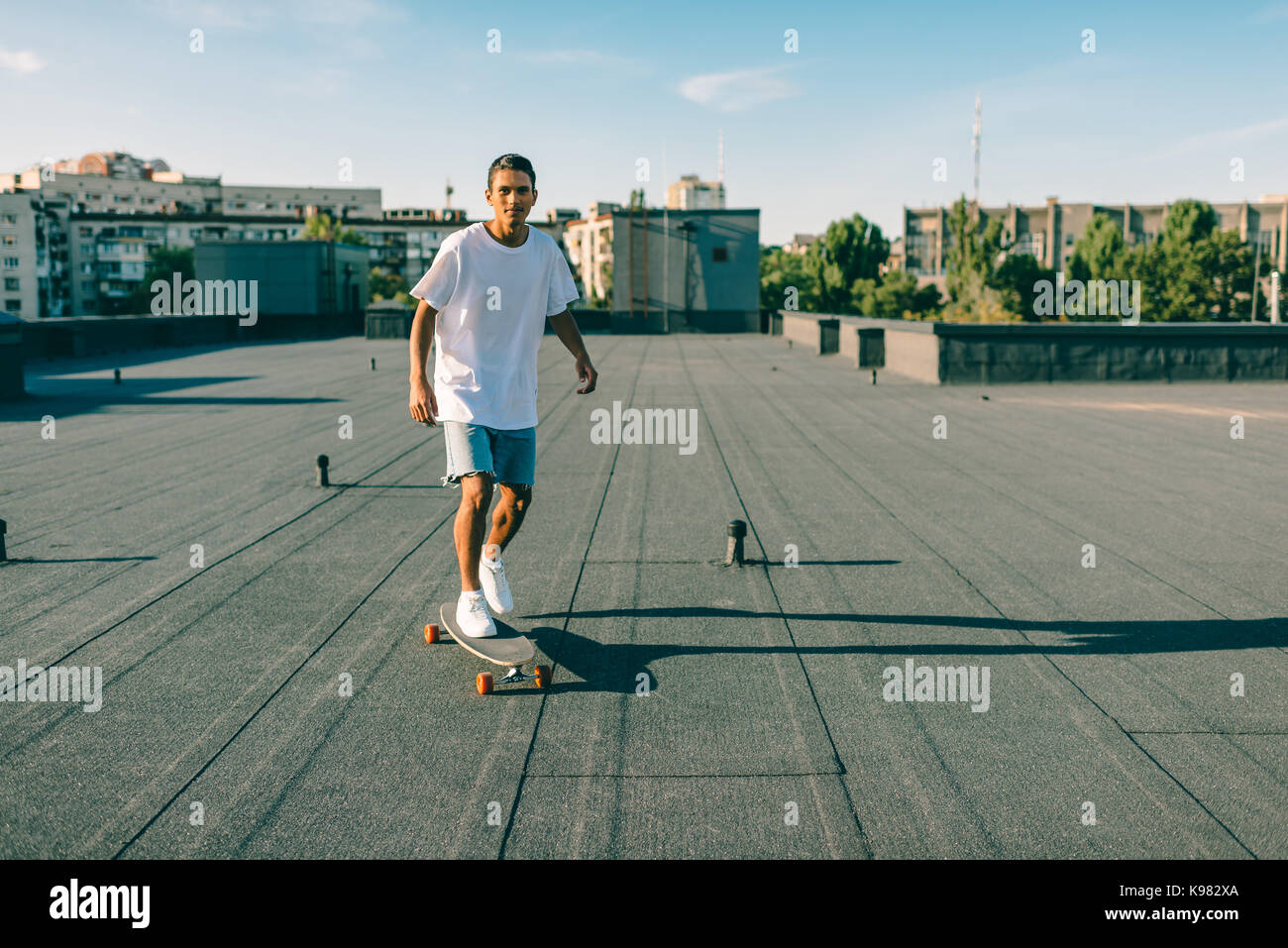 man riding skateboard on rooftop Stock Photo - Alamy