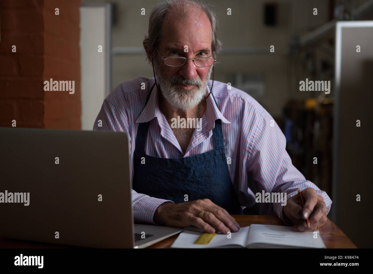Portrait goldsmith writing in book at workshop Stock Photo - Alamy