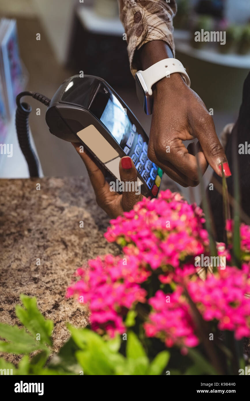 Hand of customer making payment through smartwatch in the flower shop ...