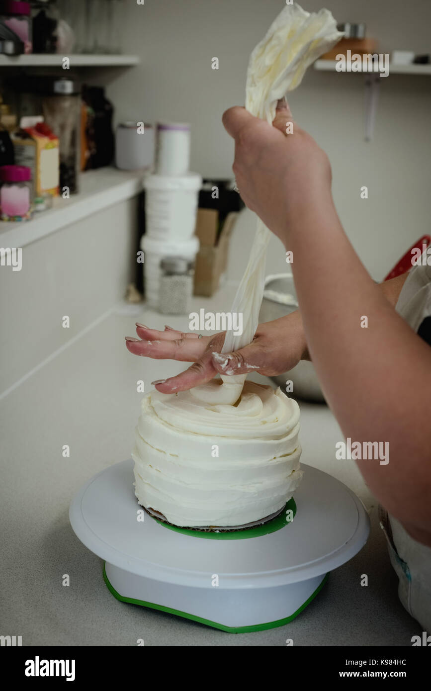 Woman icing whipped cream on cake in kitchen Stock Photo - Alamy