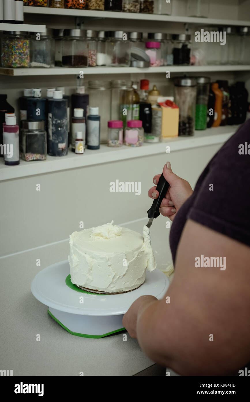 Woman spreading frosting over the cake in the kitchen Stock Photo - Alamy