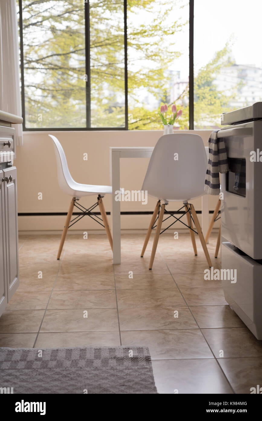 Chairs arranged around table by window in kitchen Stock Photo - Alamy