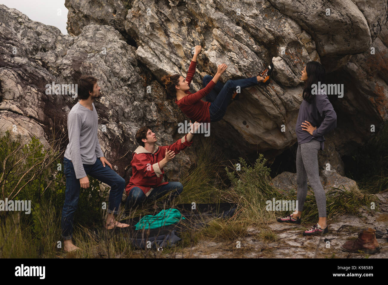 Friends assisting man in rock climbing on a sunny day Stock Photo - Alamy