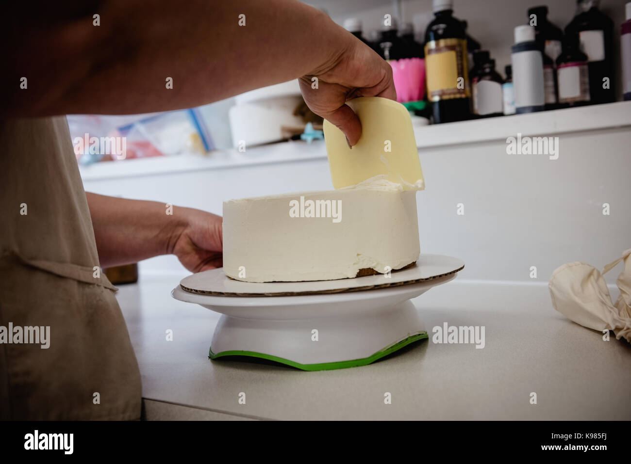 Woman spreading frosting over the cake in the kitchen Stock Photo - Alamy