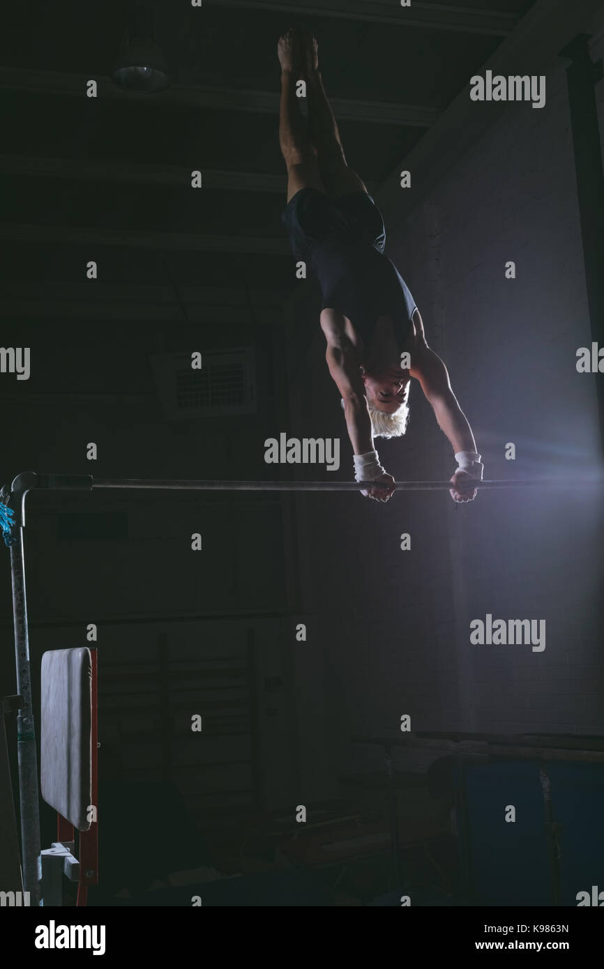 Male gymnast practicing gymnastics on the horizontal bar in the gym ...