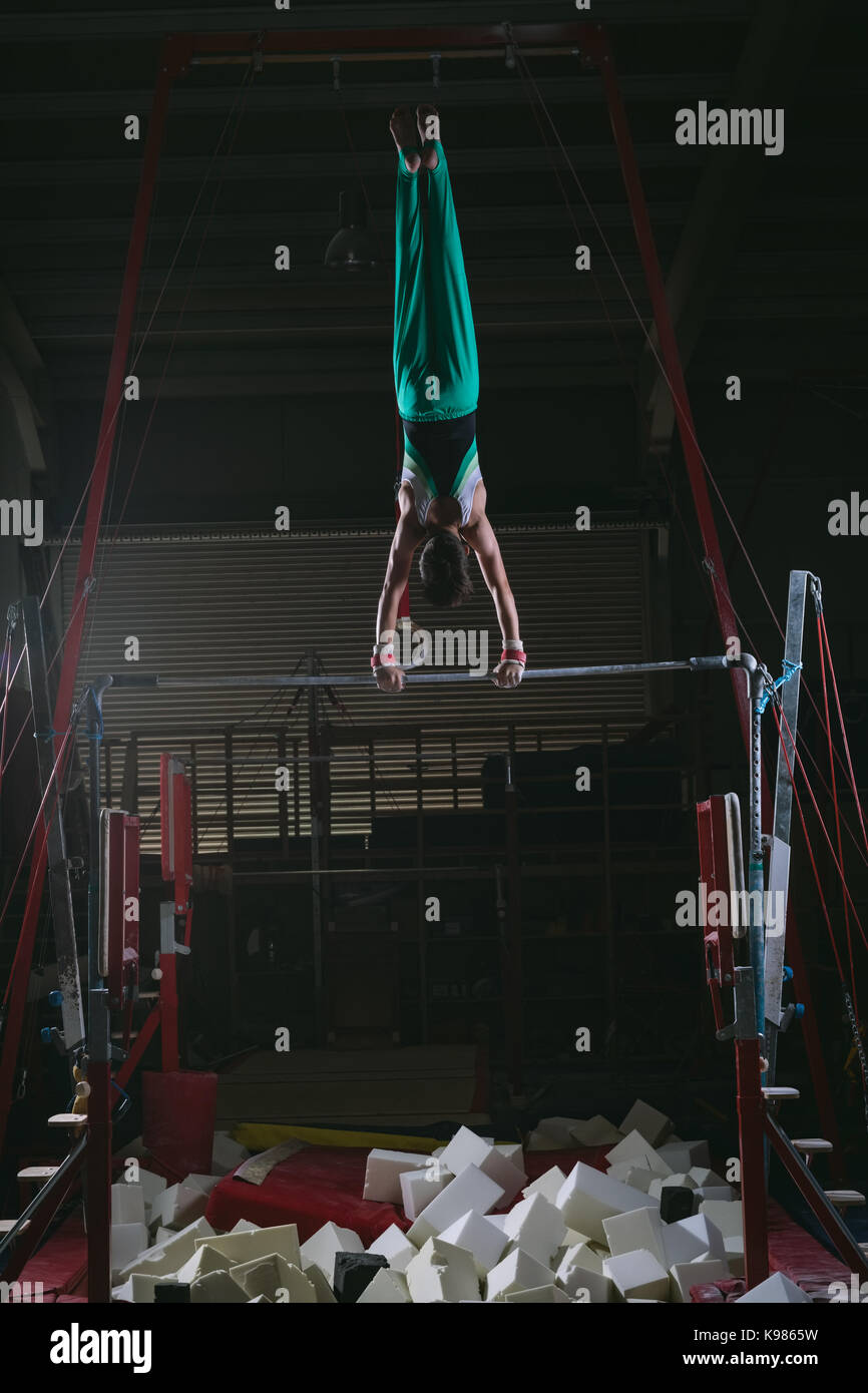 Male gymnast practicing gymnastics on the horizontal bar in the gym ...