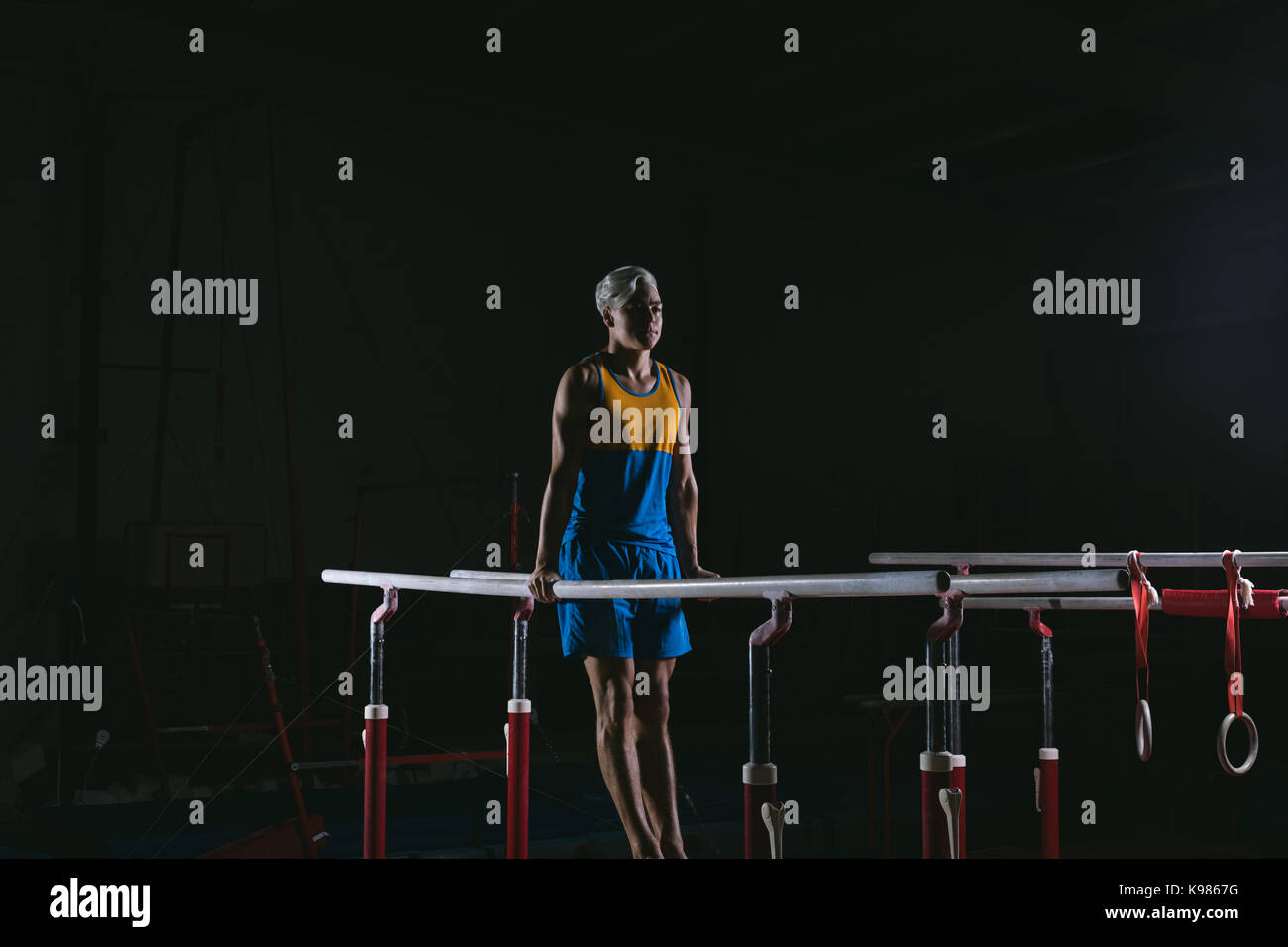 Male gymnast practicing gymnastics on the horizontal bar against black ...