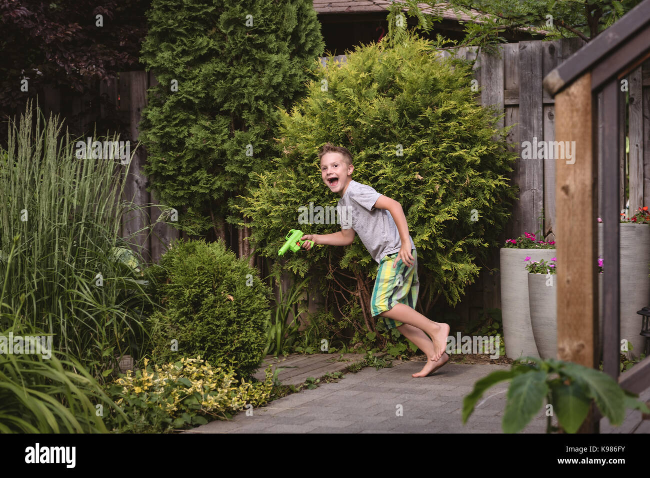 Happy boy playing with water gun in playground Stock Photo - Alamy