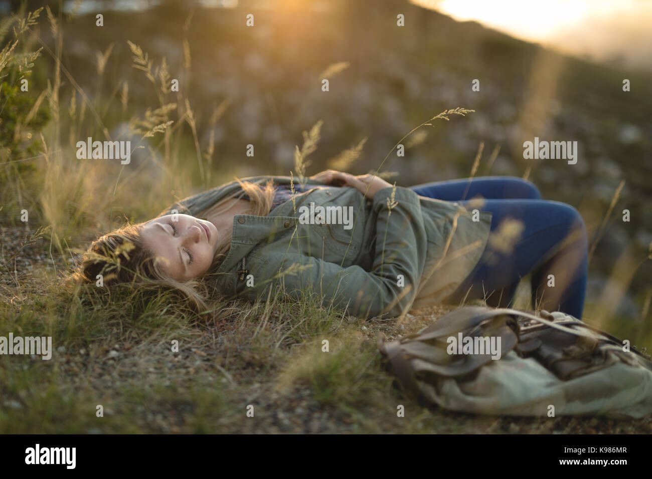 Female hiker with backpack sleeping on mountain during sunset Stock ...