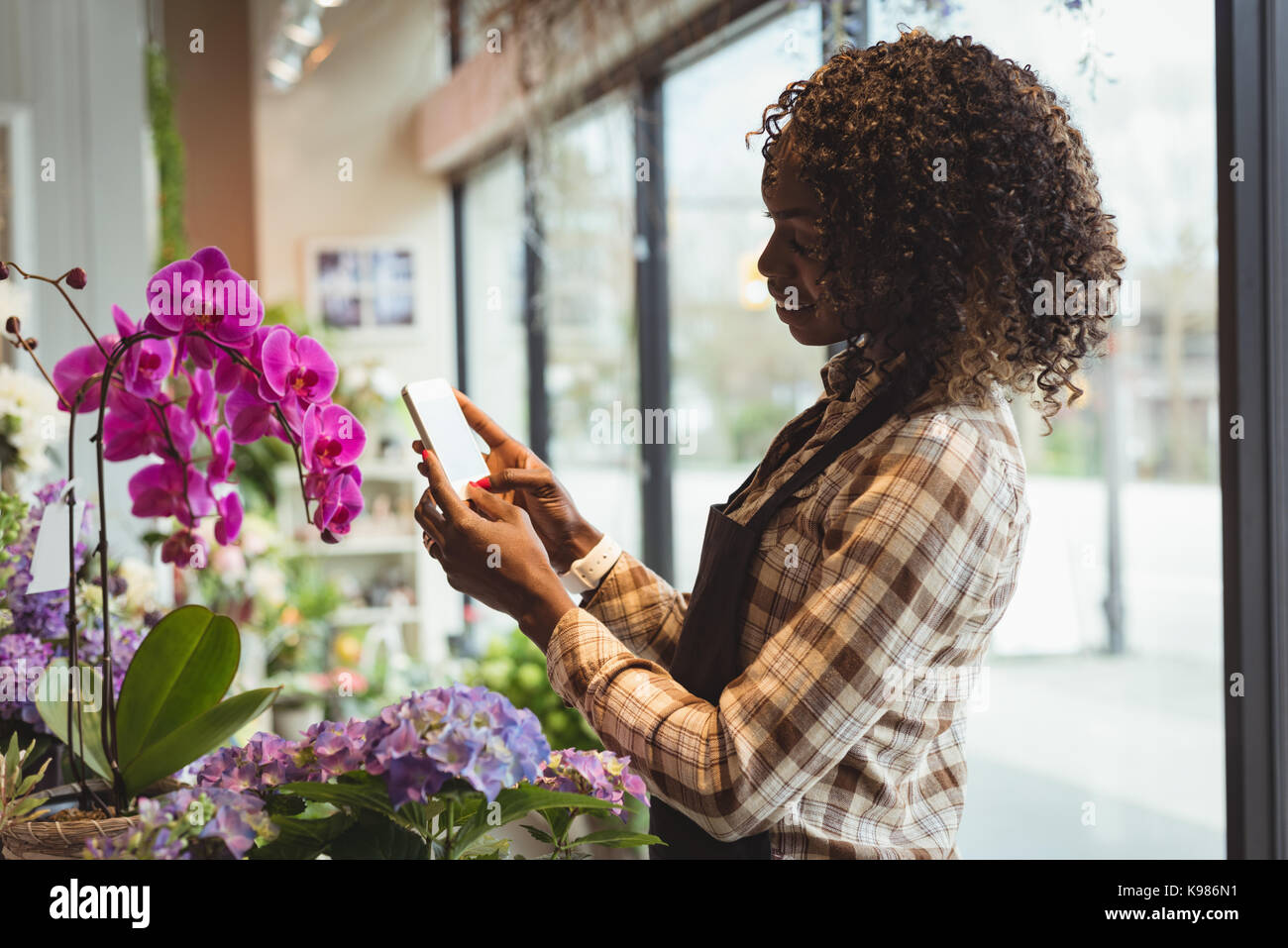 Female florist taking photograph of flower bouquet in flower shop Stock ...