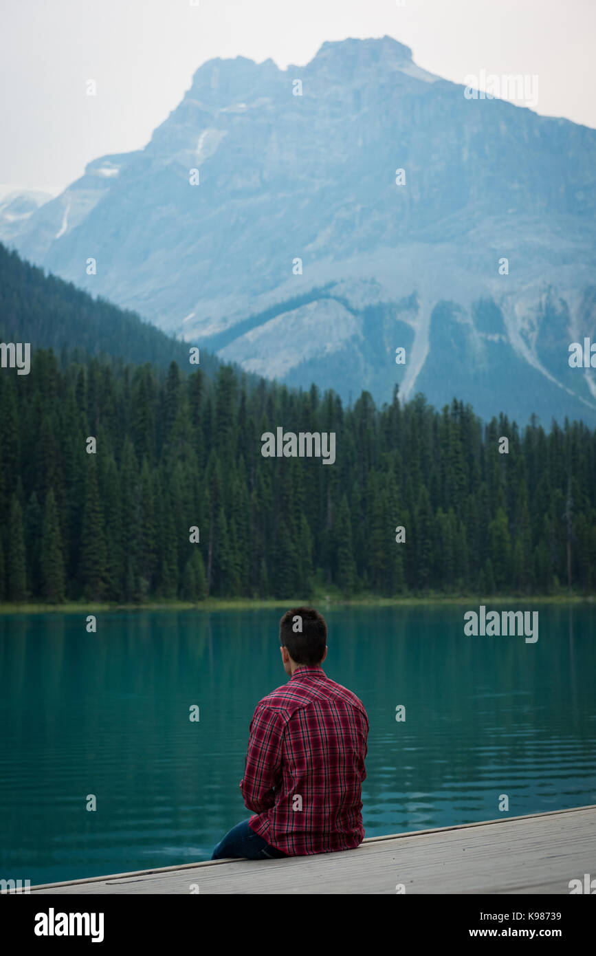 Rear view of man sitting near the lake in countryside Stock Photo - Alamy