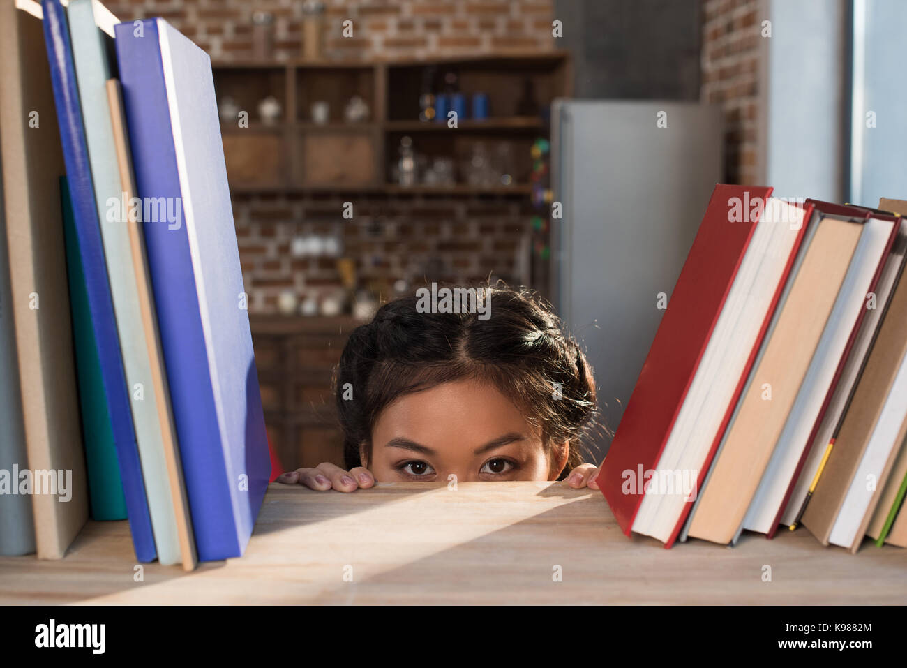 student hiding behind bookshelf Stock Photo - Alamy