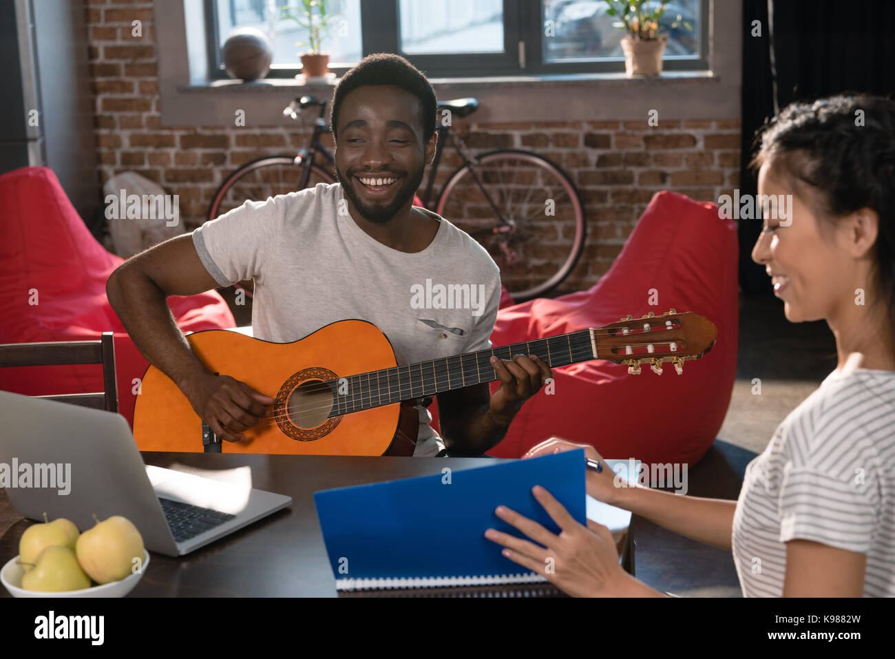 girl studying while student playing guitar Stock Photo - Alamy