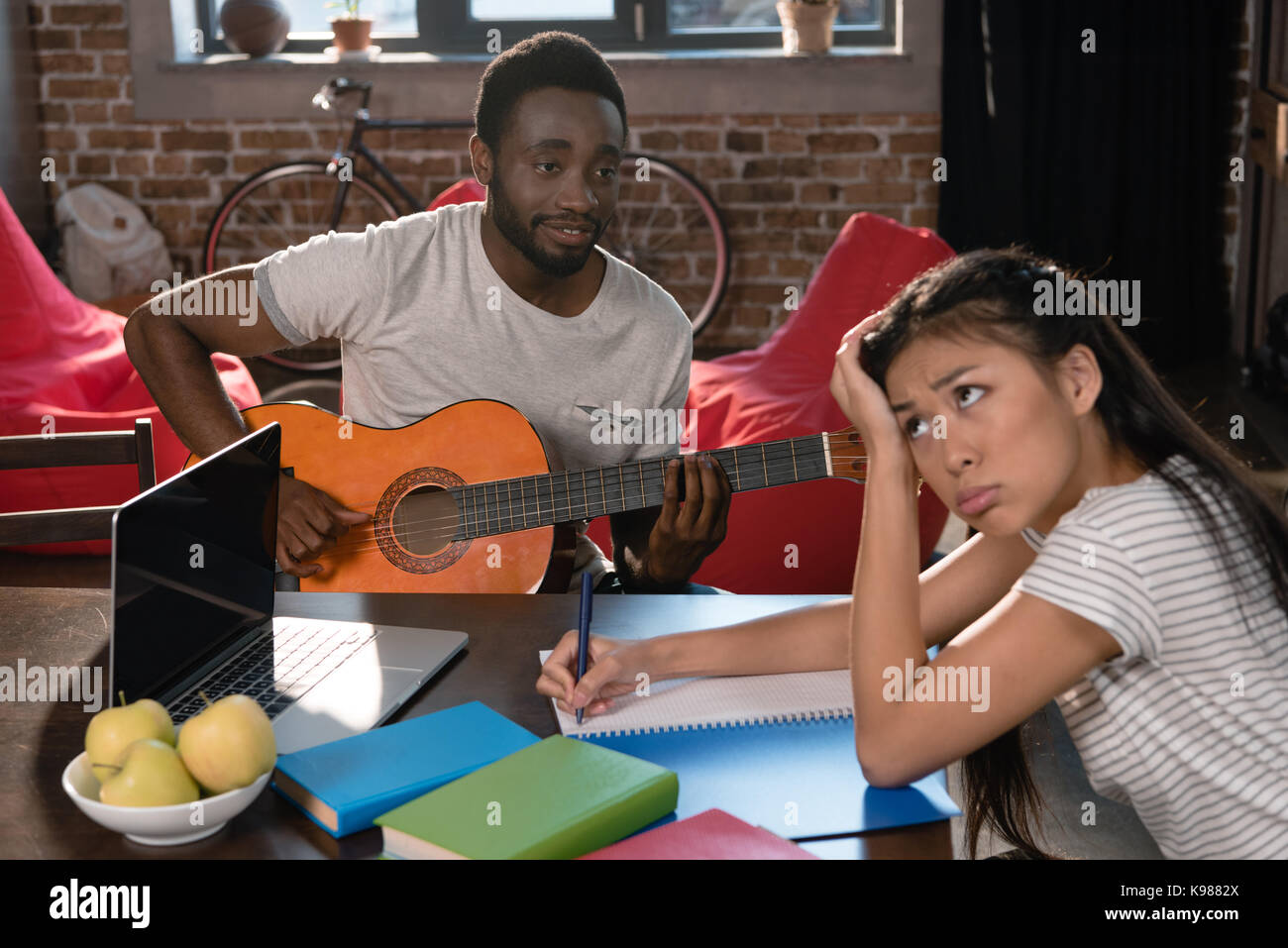 girl studying while student playing guitar Stock Photo - Alamy