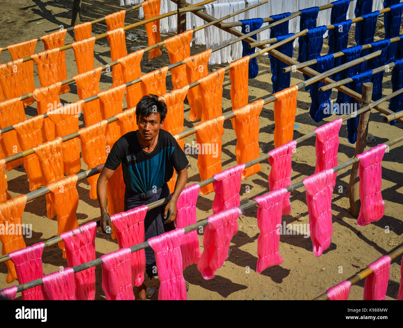 Mandalay, Myanmar - Feb 11, 2017. A man drying colorful fabric after ...