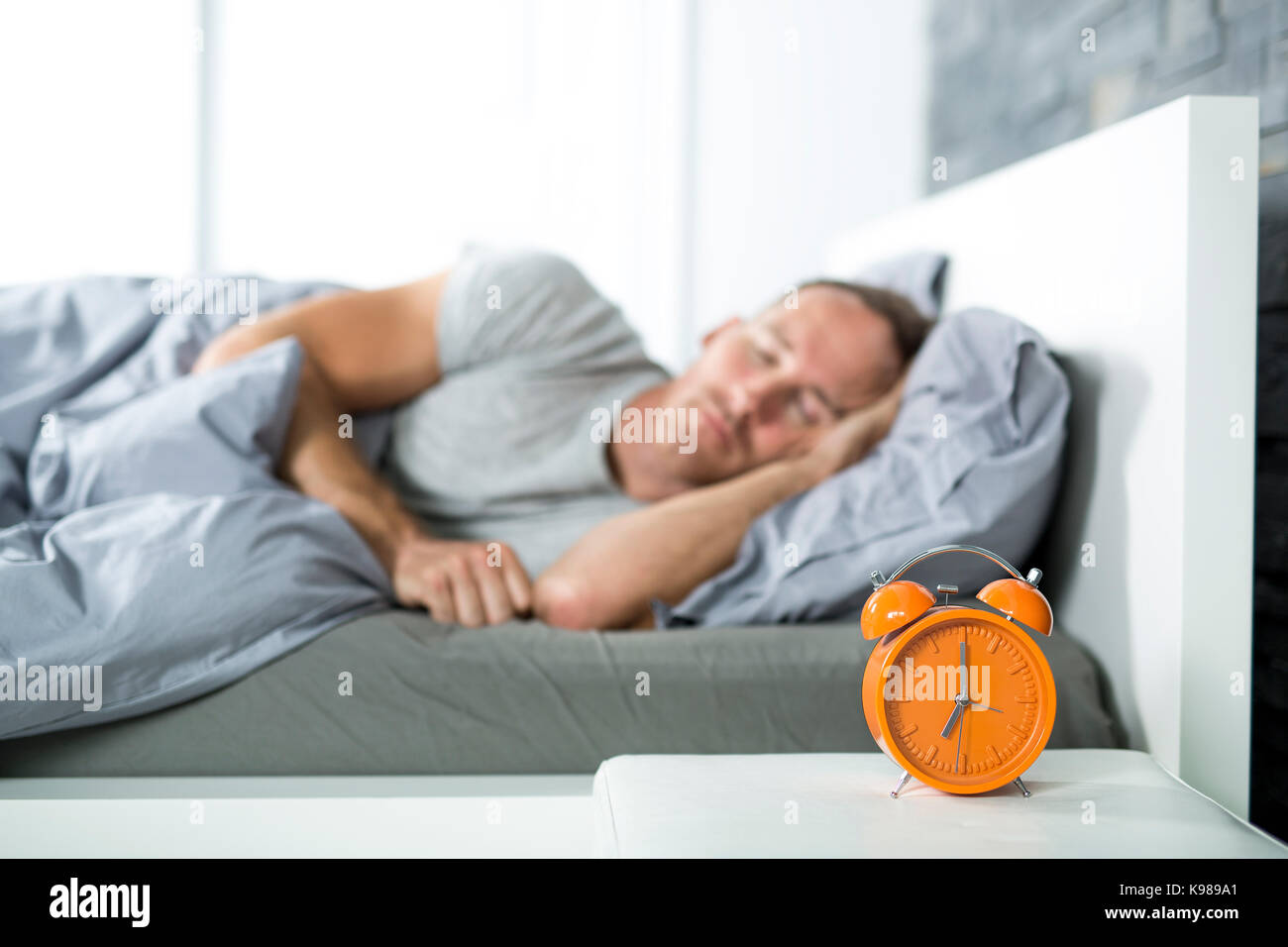 Time to wake up. Tired man in the bed not happy Stock Photo - Alamy