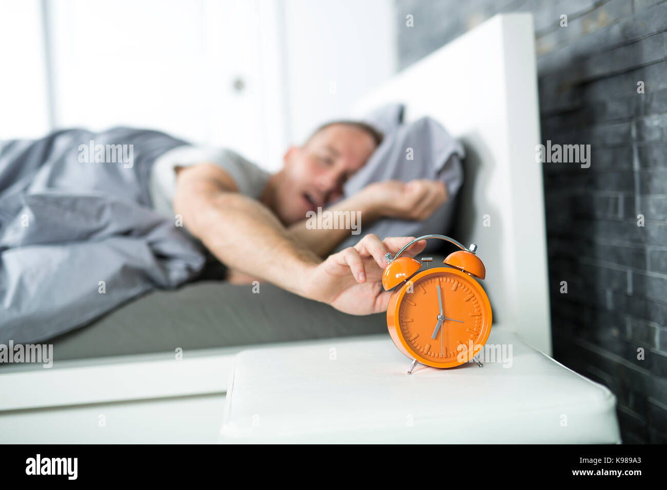 Time to wake up. Tired man in the bed not happy Stock Photo - Alamy