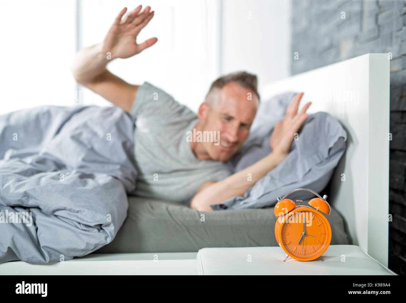 Time to wake up. Tired man in the bed not happy Stock Photo - Alamy