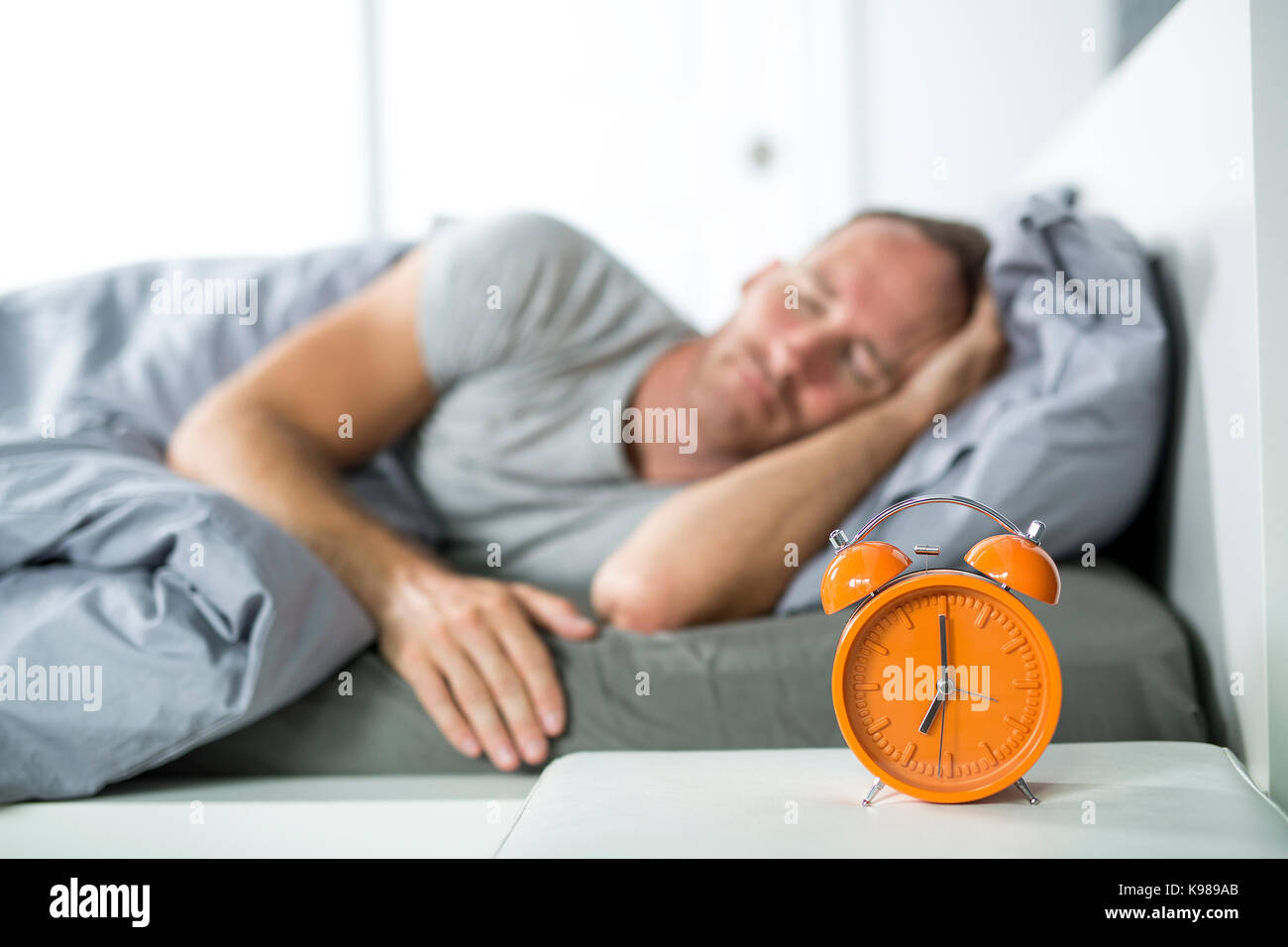 Time to wake up. Tired man in the bed not happy Stock Photo - Alamy
