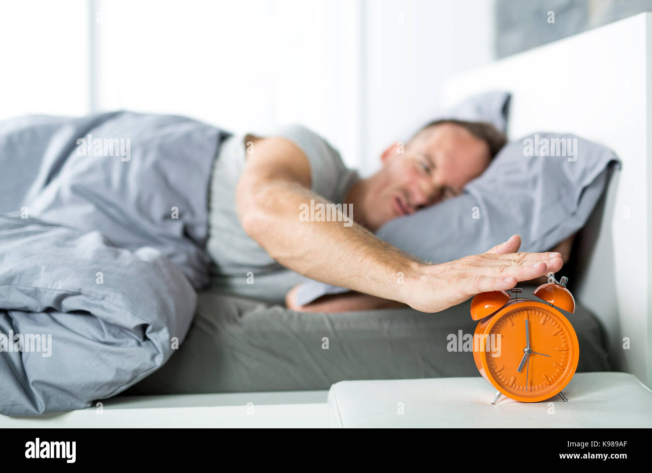 Time to wake up. Tired man in the bed not happy Stock Photo - Alamy