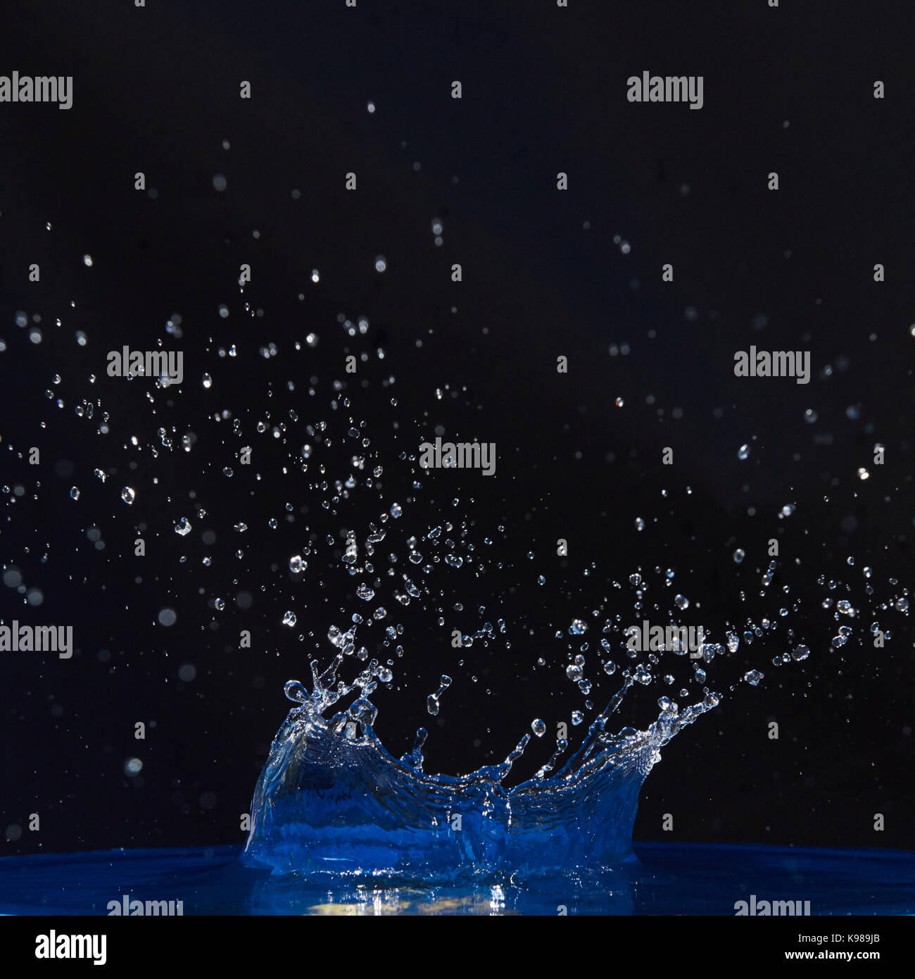 Splash of water crown on blue surface Stock Photo - Alamy