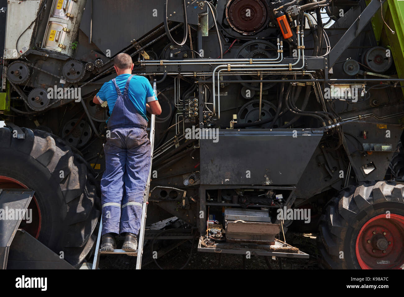 Combine machine service, mechanic repairing motor outdoors Stock Photo ...